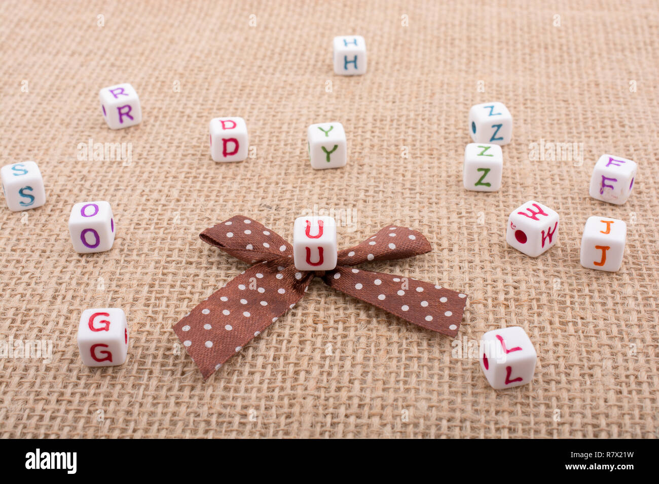 A ribbon and scattered dice-sized alphabet cubes on a textured surface ...