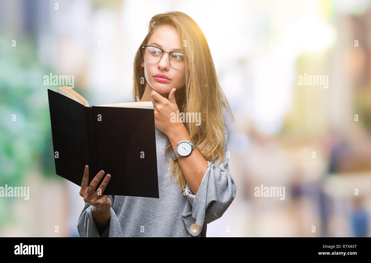 Young beautiful blonde woman reading a book over isolated background ...