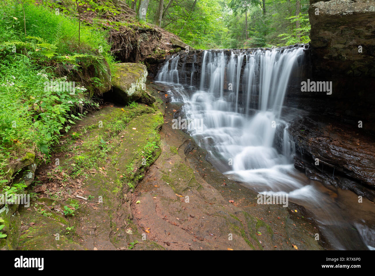 Slabs of rock creating a swirling pattern around the waterfall along ...