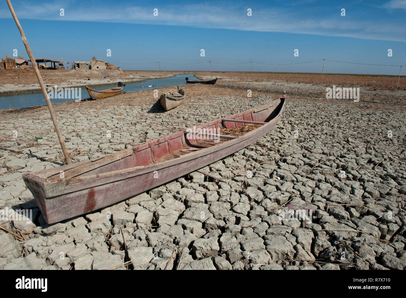 A traditional Marsh Arab boat seen laying idle on dry and cracked Marsh ...