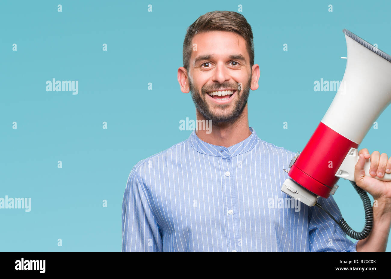 Young handsome man yelling through megaphone over isolated background ...