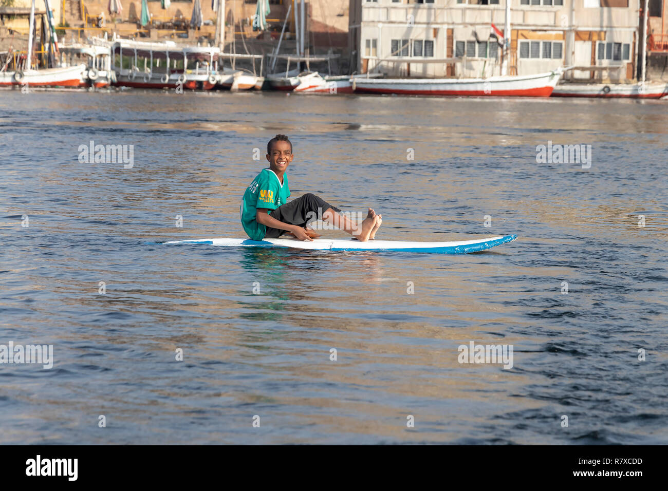 Aswan, Egypt - September 13, 2018: Egyptian kid in a surf board in Nile ...