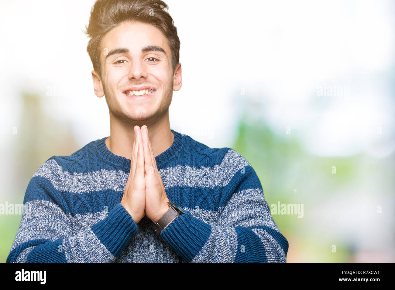 Young handsome man over isolated background praying with hands together ...