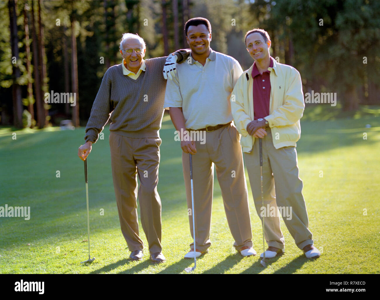 Three golf enthusiasts pose for the camera with putters in hand Stock ...