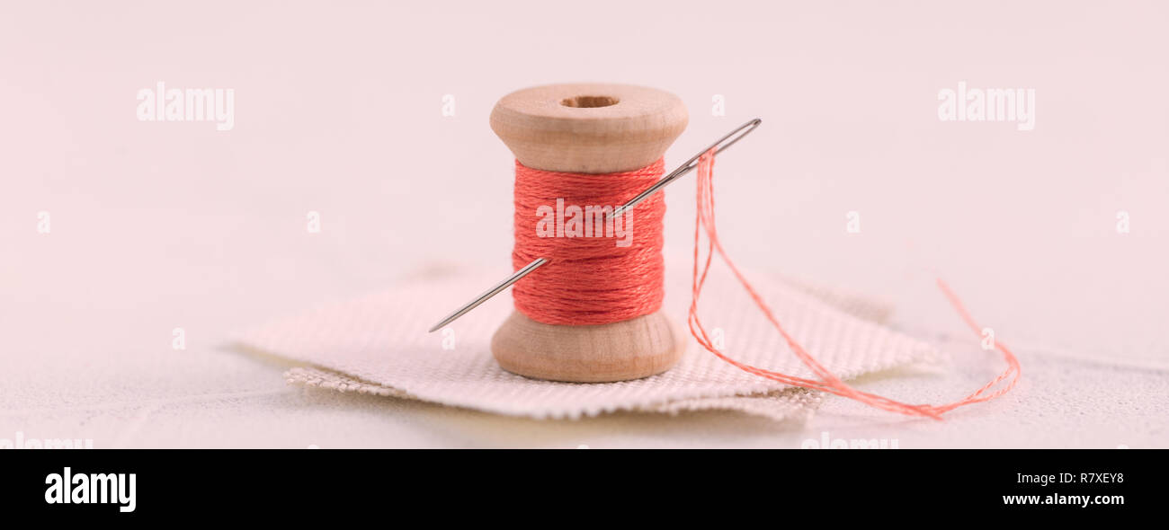 Trendy coral colored threads wooden bobbin for stitching with a needle ...