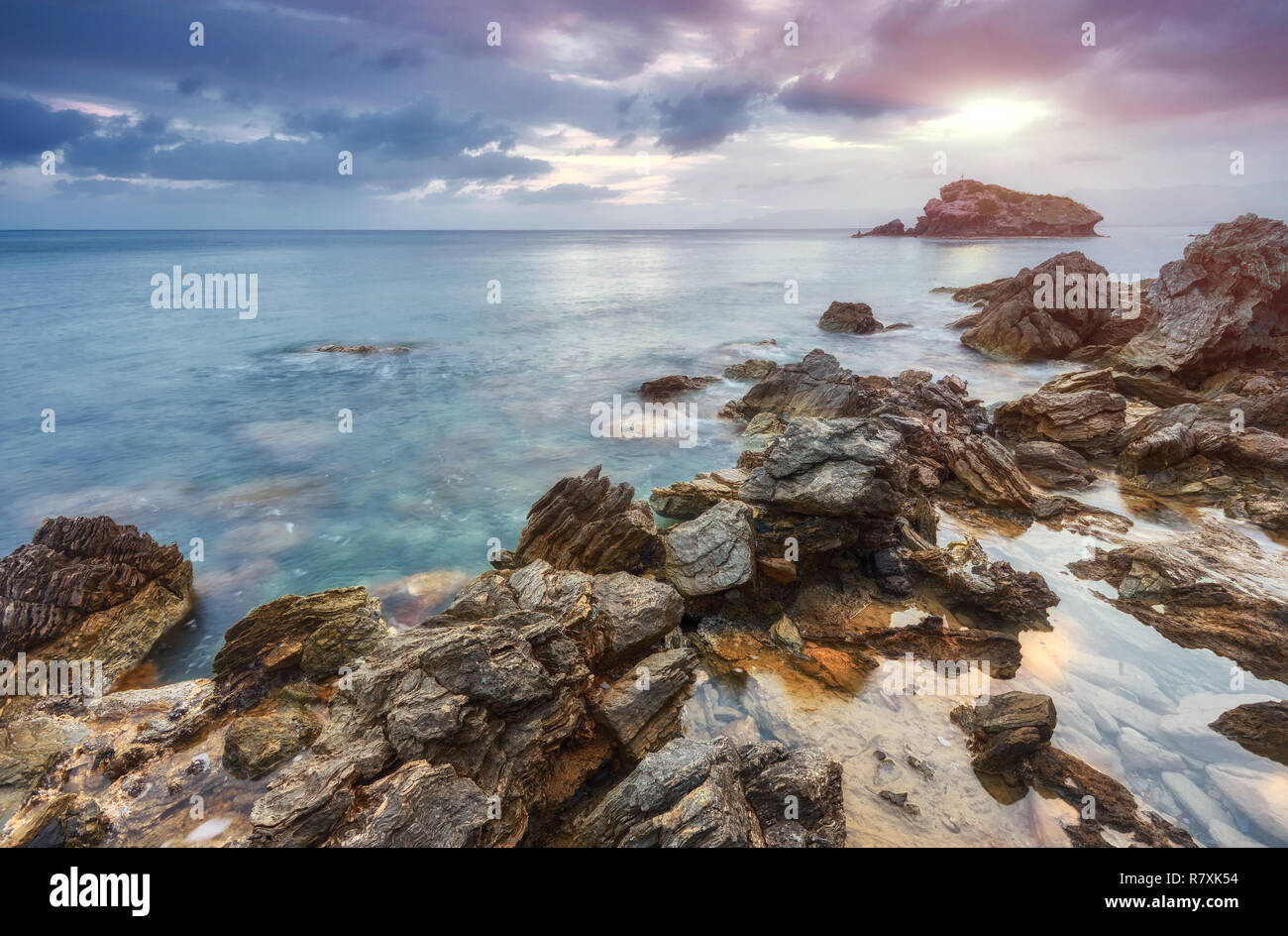 Stones and rocks in forefront with creamy surf ebbing and flowing on ...
