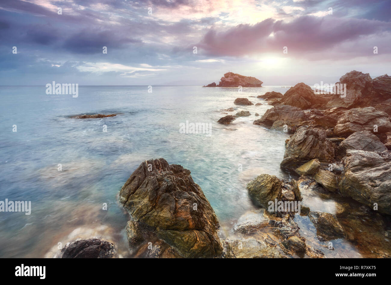 Stones and rocks in forefront with creamy surf ebbing and flowing on ...
