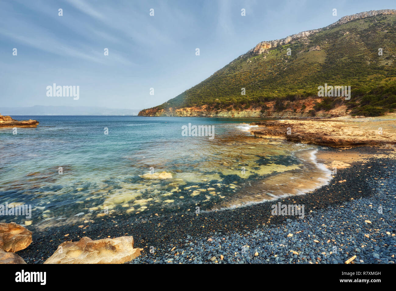 Stones and rocks in forefront with creamy surf ebbing and flowing on ...