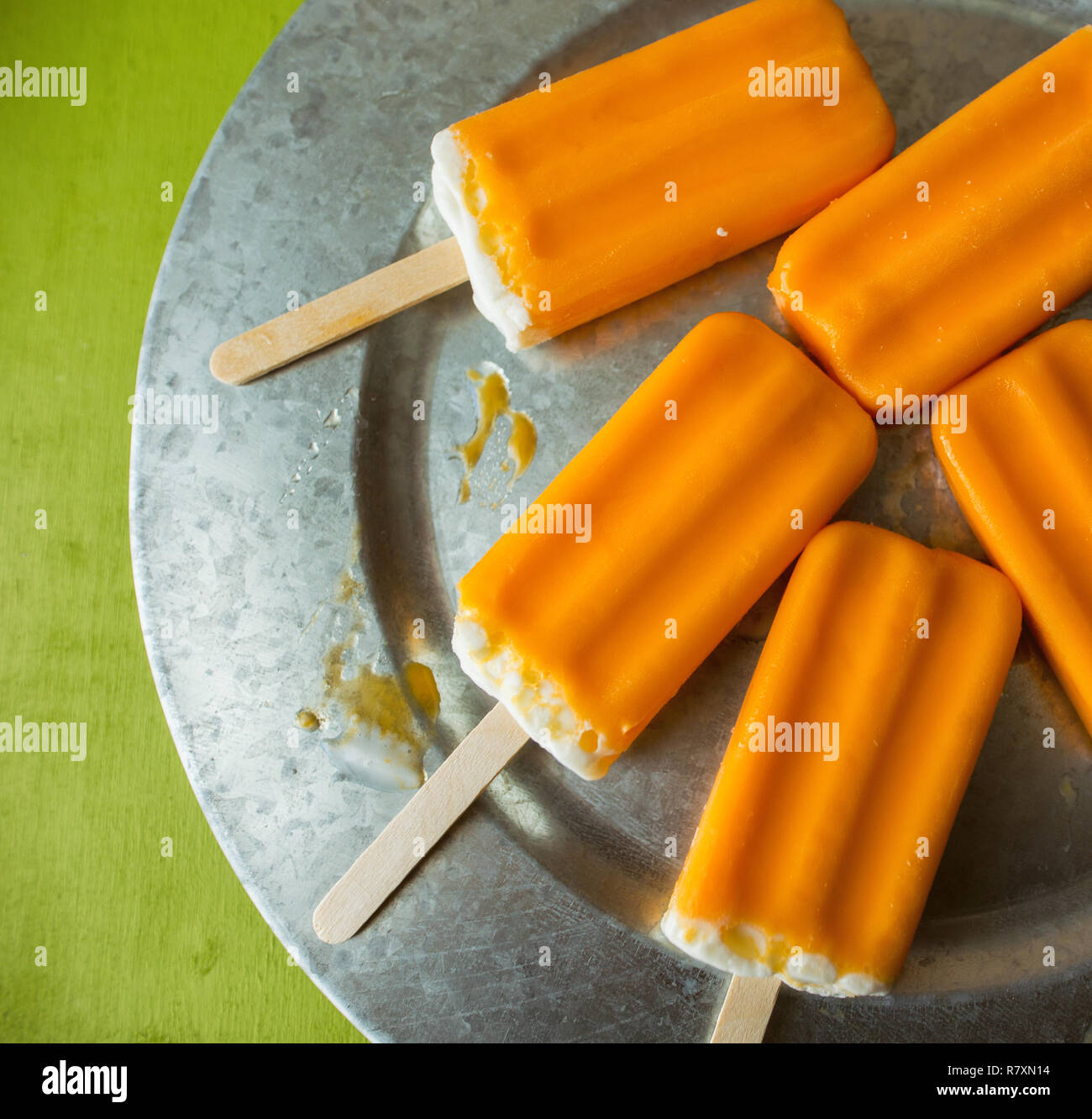 Several orange and vanilla creamsicles on a galvanized steel plate and ...