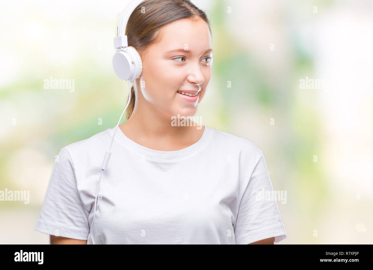 Young caucasian woman listening to music wearing headphones over ...