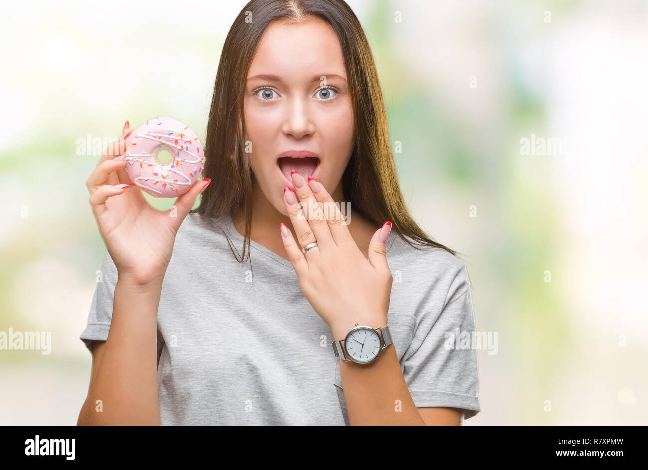 Young caucasian woman eating sweet donut over isolated background cover ...