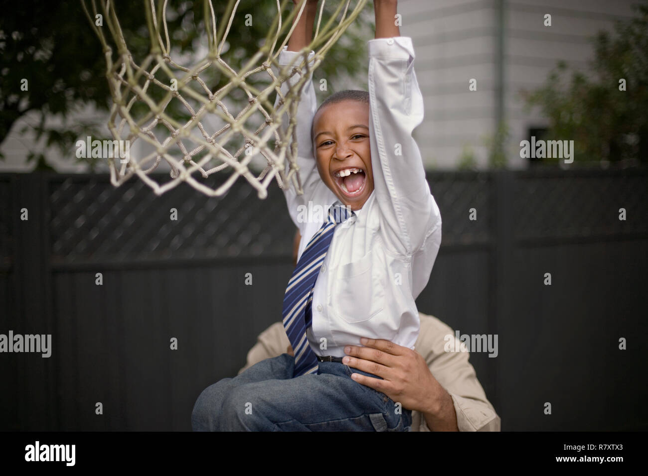 Portrait of a laughing boy hanging from a basketball hoop Stock Photo ...