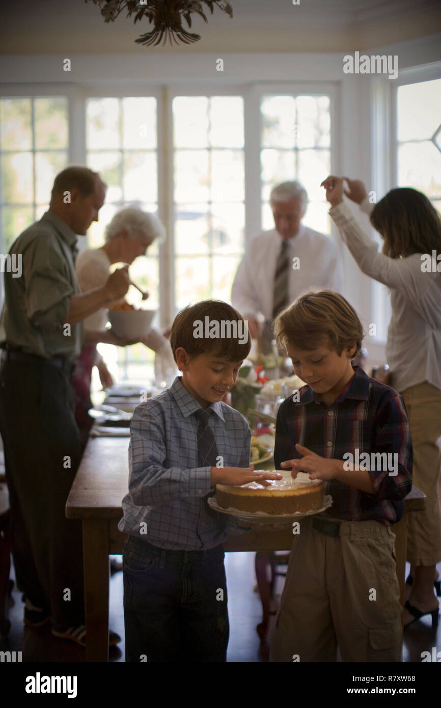 Two young boys tasting the icing off a cake Stock Photo - Alamy