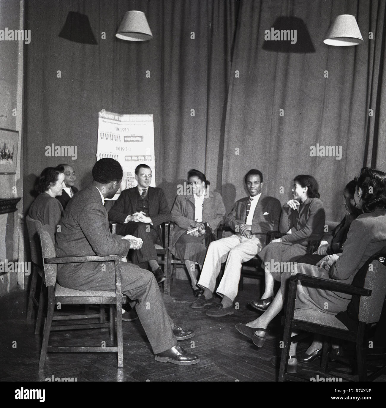 1950s, historical, seated in a room, a group of newly arrived foreign ...
