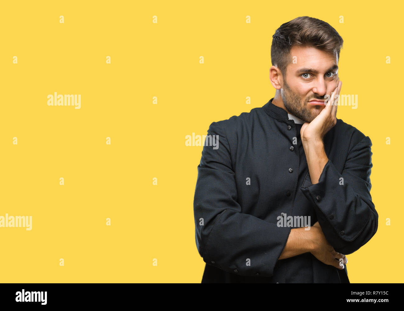 Young catholic christian priest man over isolated background thinking ...