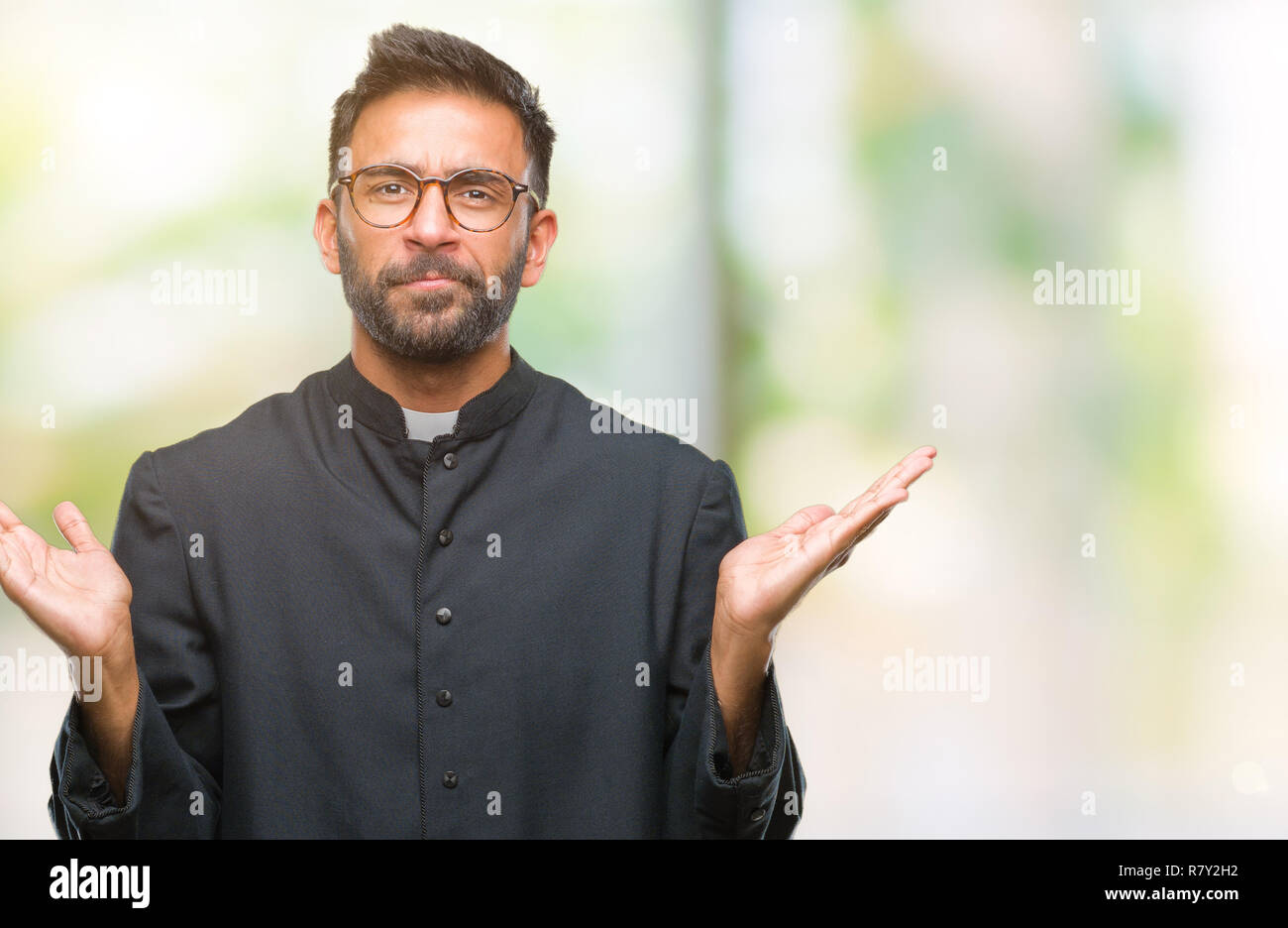 Adult hispanic catholic priest man over isolated background clueless ...