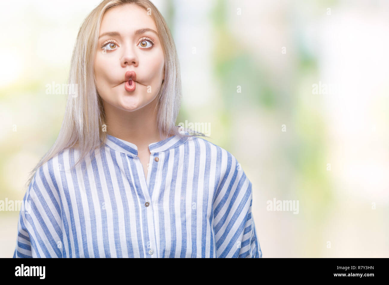 Young blonde woman over isolated background making fish face with lips ...