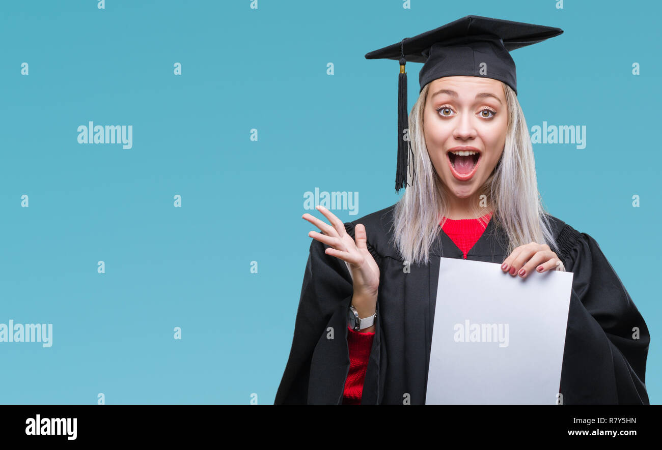 Young blonde woman wearing graduate uniform holding degree over ...