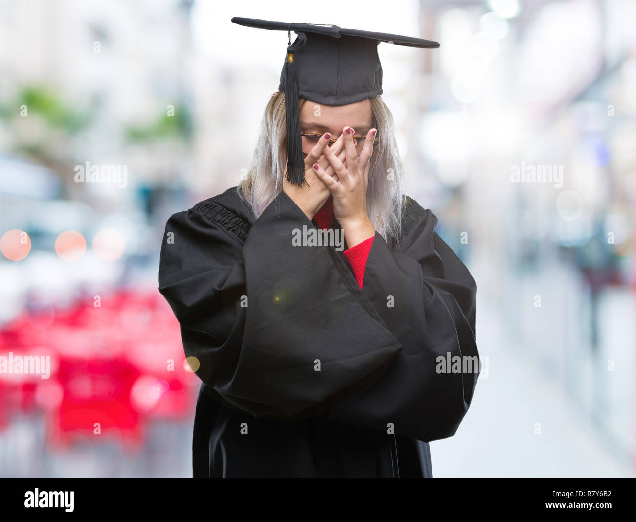 Young blonde woman wearing graduate uniform over isolated background ...