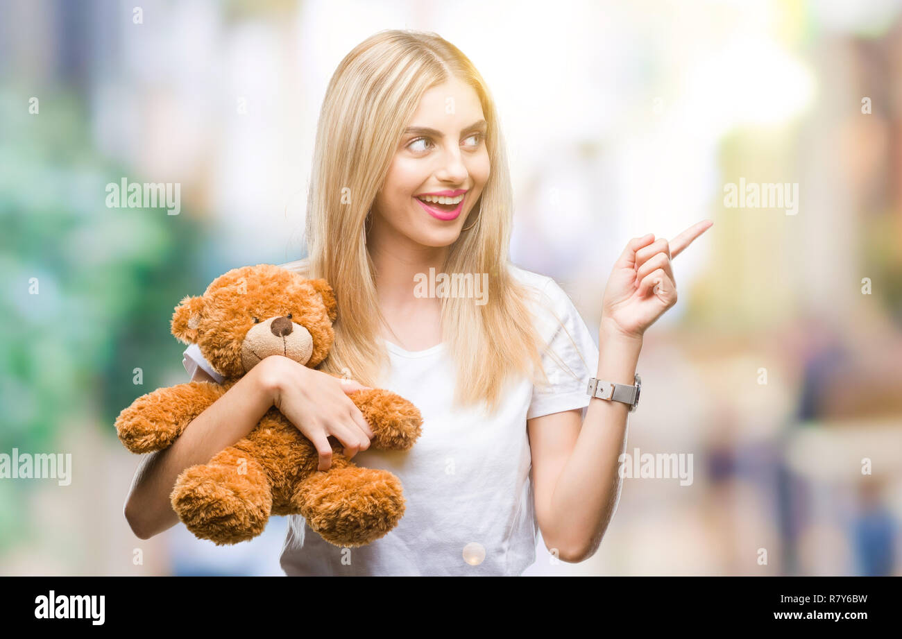 Young beautiful blonde woman holding teddy bear over isolated ...
