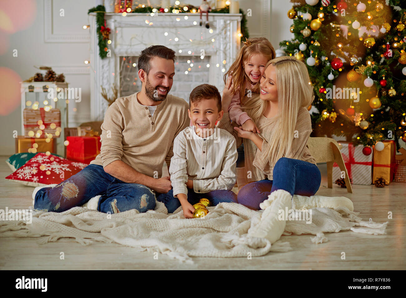 Happy family with gift boxes sitting near Christmas tree on Christmas ...