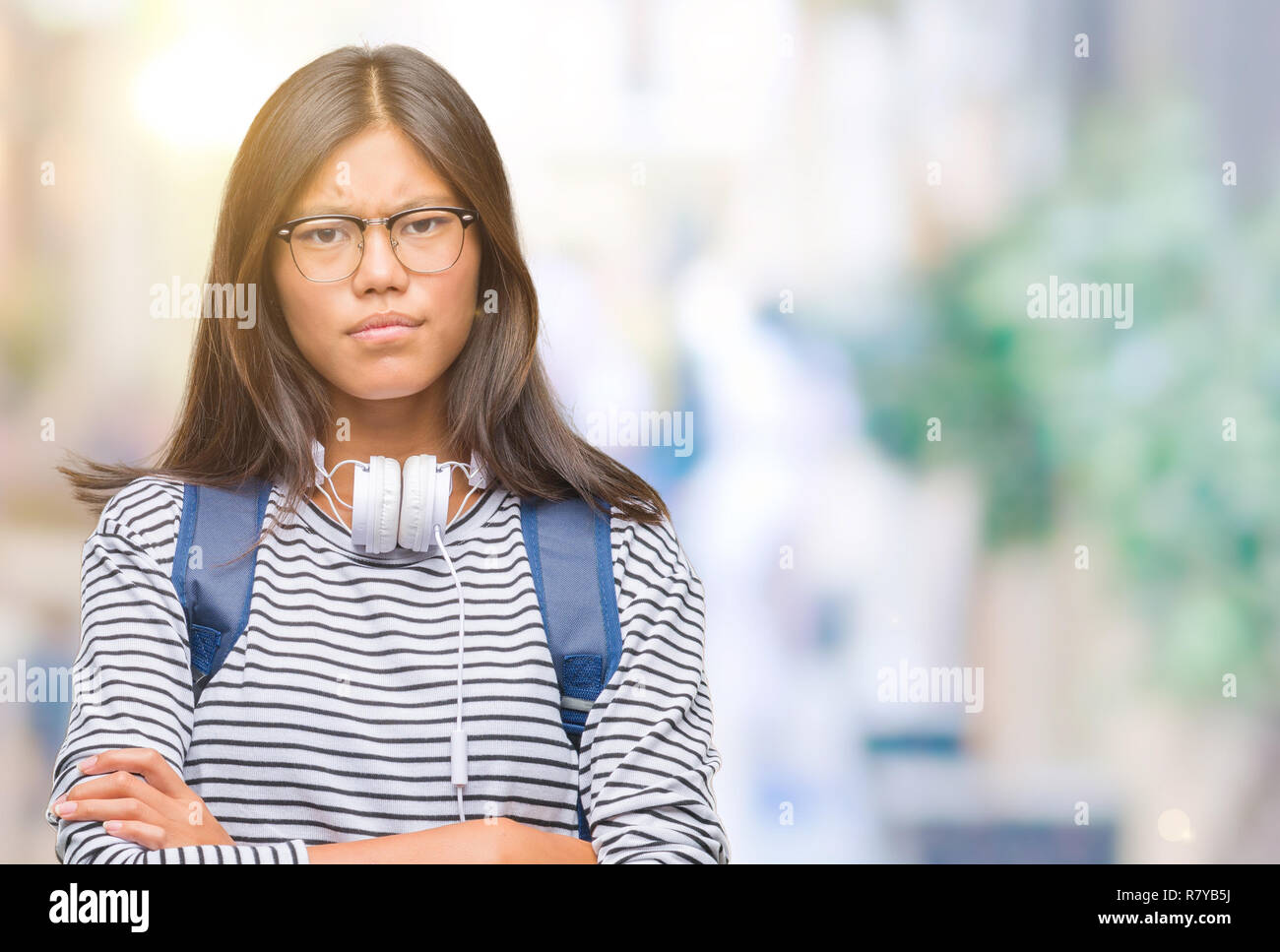 Young asian student woman wearing headphones and backpack over isolated ...