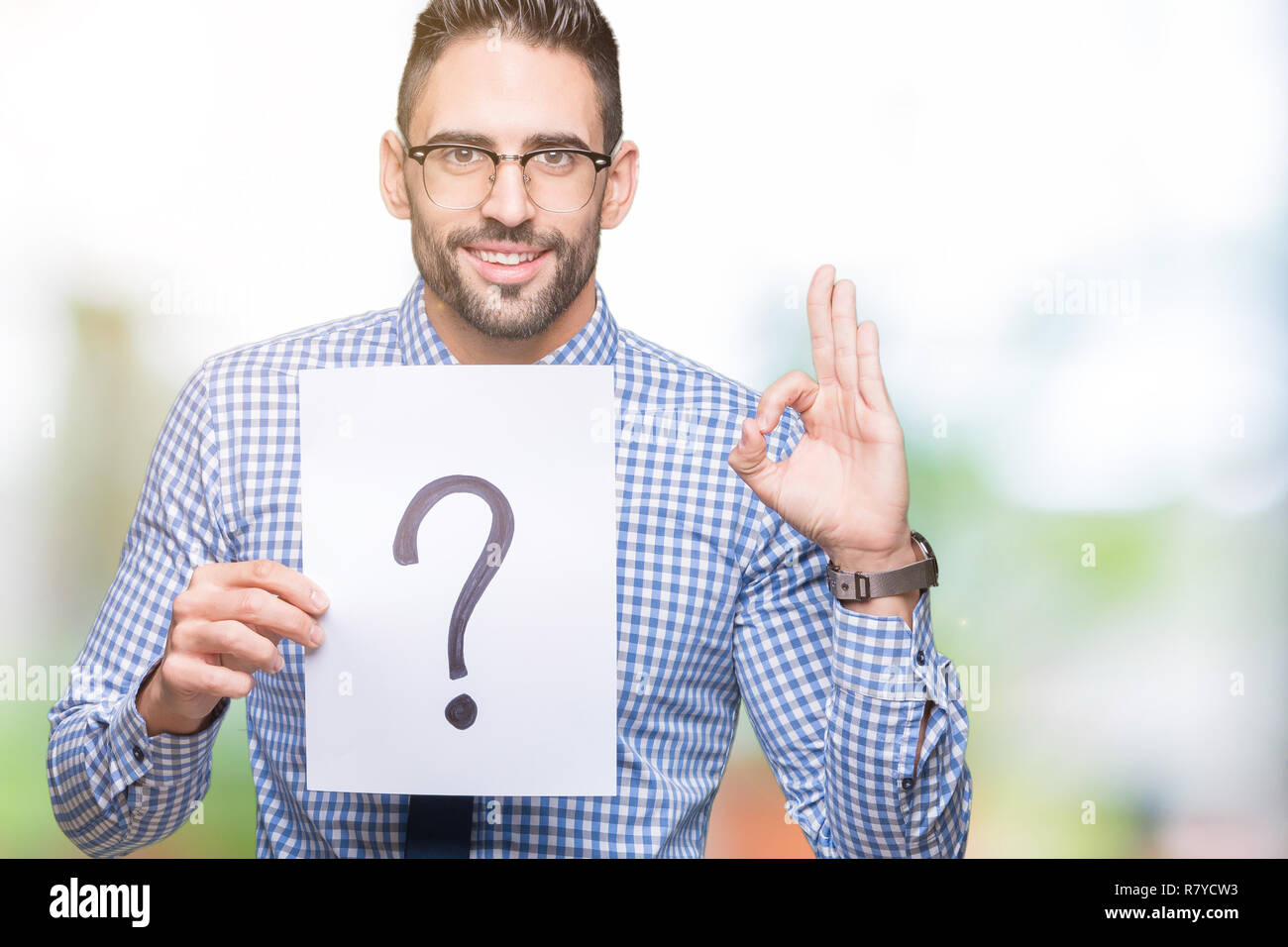 Handsome young business man holding paper with question mark over ...