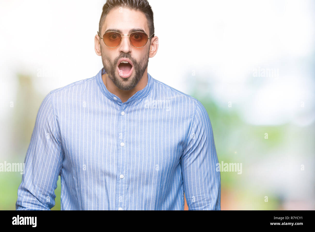 Young handsome man wearing sunglasses over isolated background afraid and shocked with surprise ...