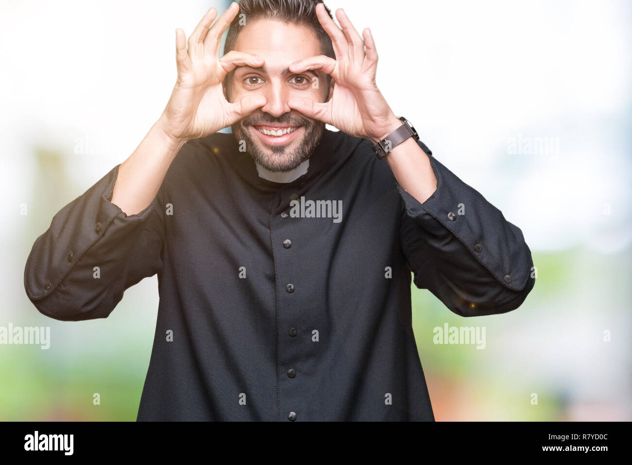 Young Christian priest over isolated background Trying to open eyes ...