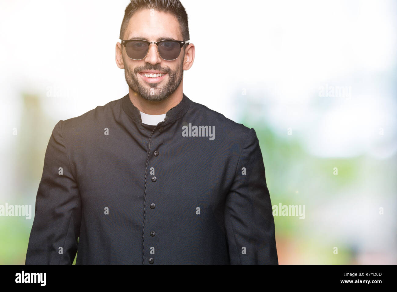 Young Christian priest wearing sunglasses over isolated background with ...