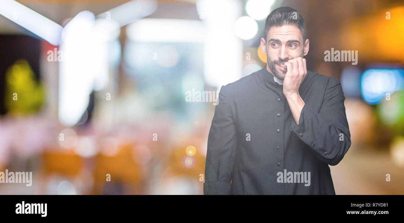 Young Christian priest over isolated background looking stressed and ...