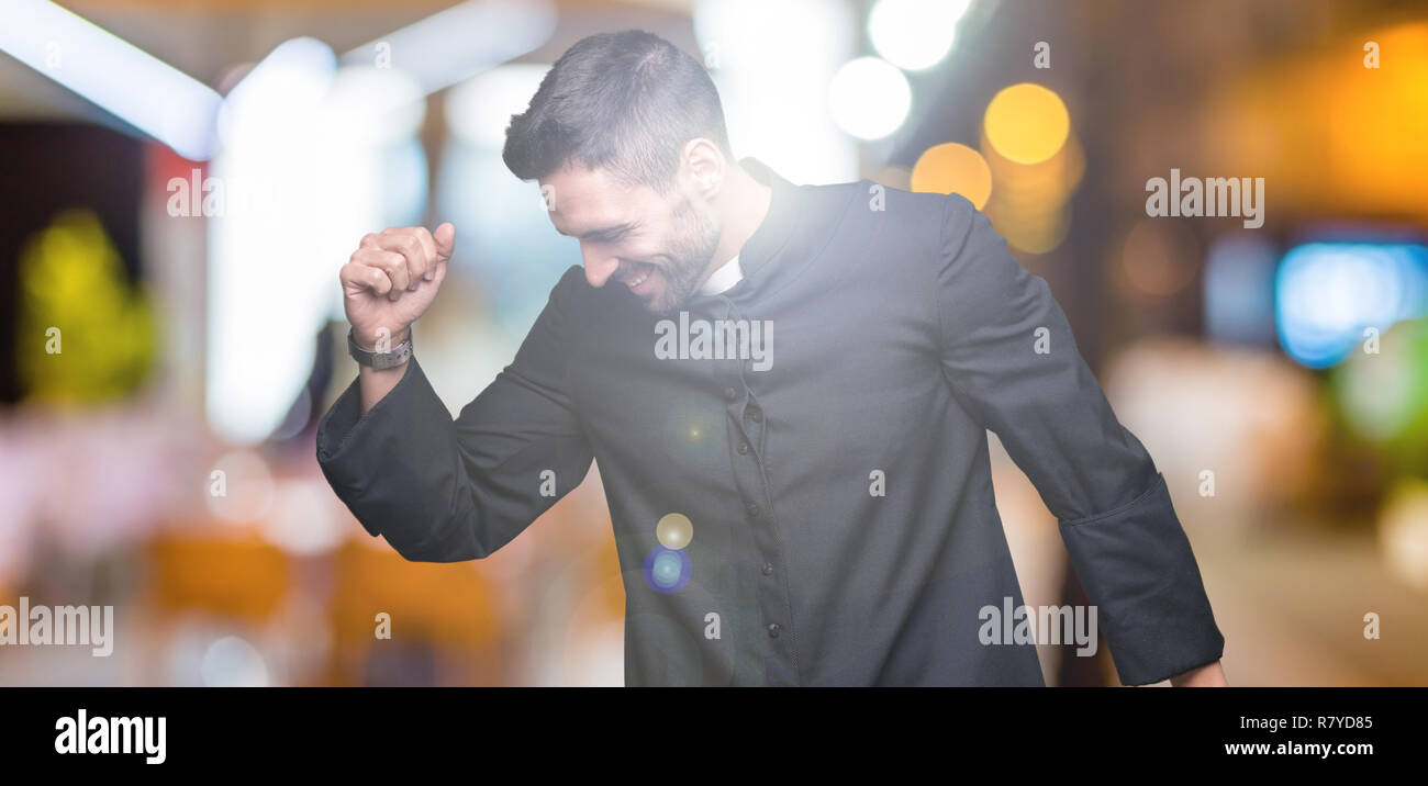Young Christian priest over isolated background Dancing happy and ...