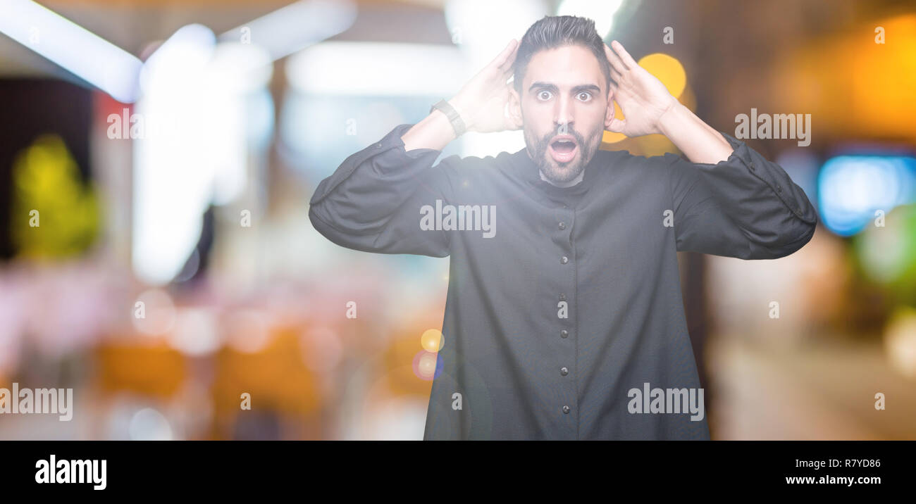 Young Christian priest over isolated background Crazy and scared with ...