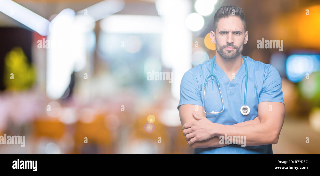 Handsome young doctor surgeon man over isolated background skeptic and ...