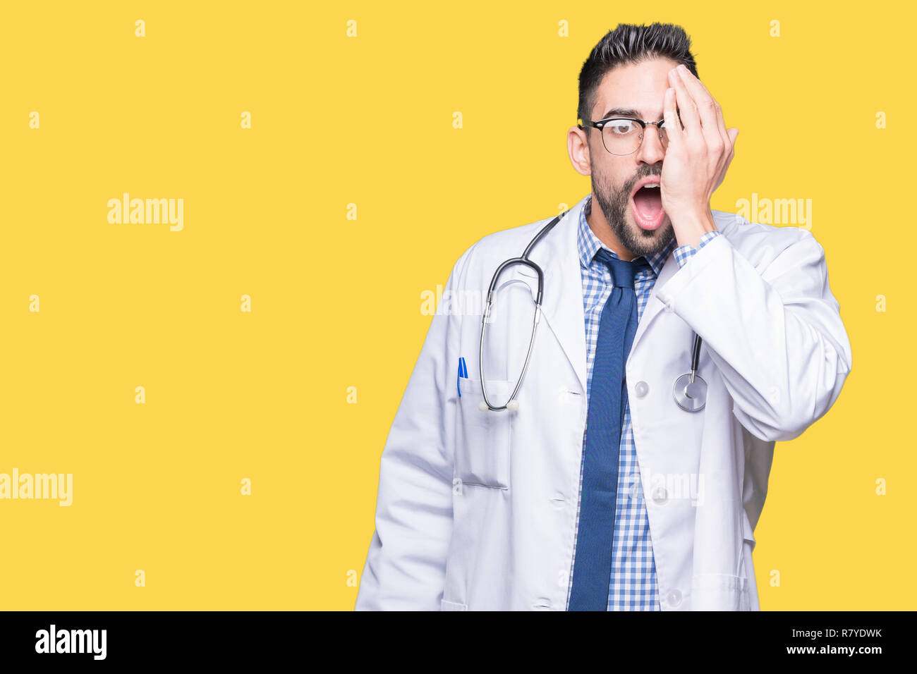Handsome young doctor man over isolated background covering one eye ...