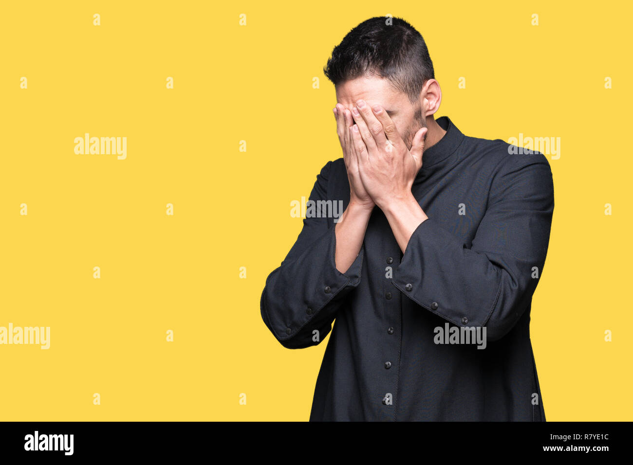 Young Christian priest over isolated background with sad expression ...