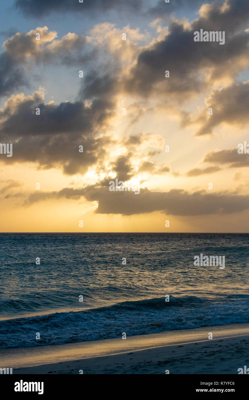 Sunset on Divi beach Aruba - quite ocean waves reflect the sun ...