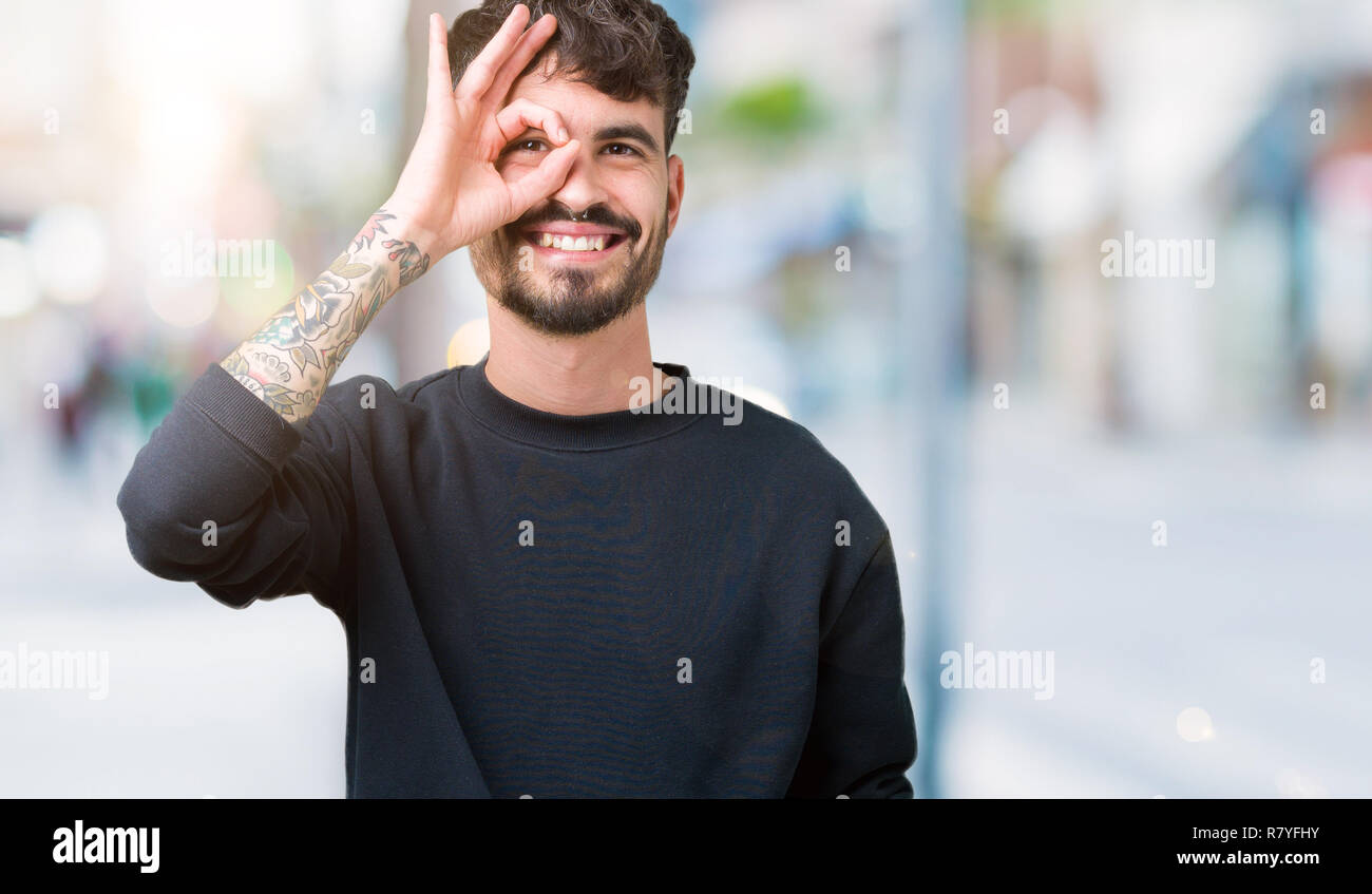 Young handsome man over isolated background doing ok gesture with hand ...