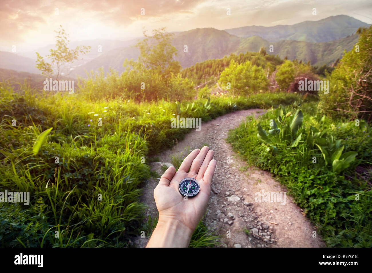Hand with compass at mountain road at sunset sky in Kazakhstan, central ...
