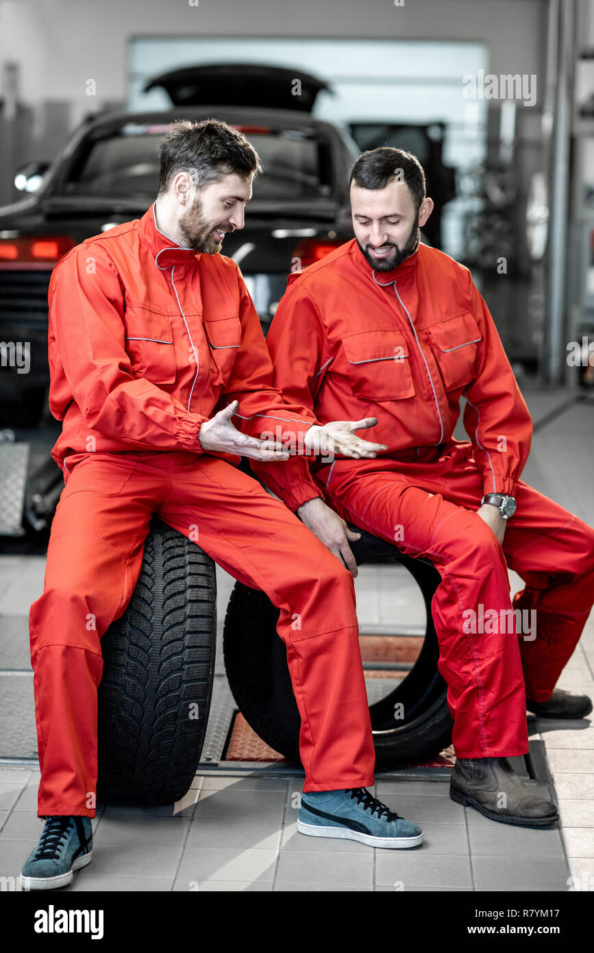 Car service workers in red uniform having a break sitting together on ...