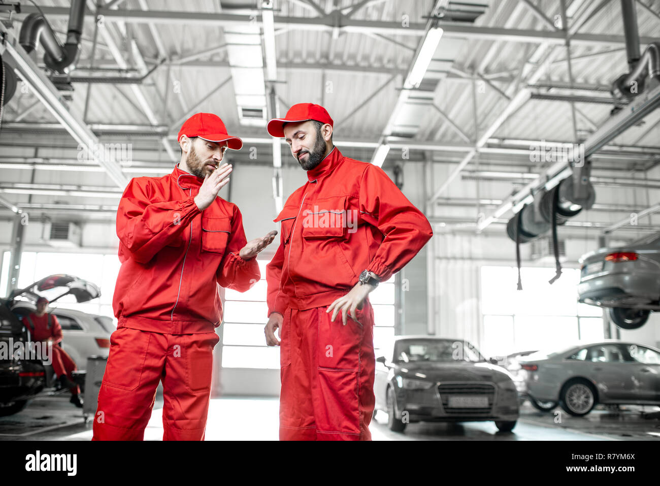 Two auto mechanics in red uniform talking together during the break at ...