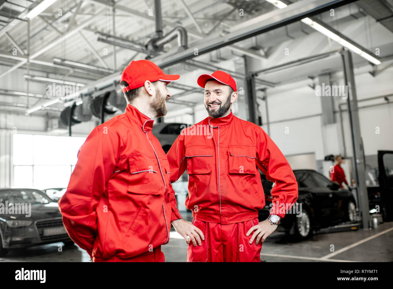 Two auto mechanics in red uniform talking together during the break at ...