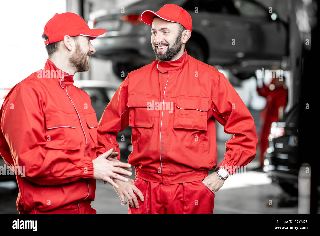 Two auto mechanics in red uniform talking together during the break at ...
