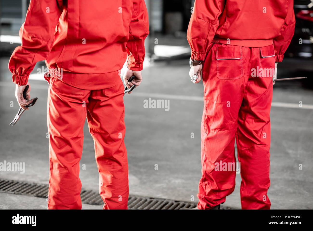 Two auto mechanics in red uniform standing together at the car service ...