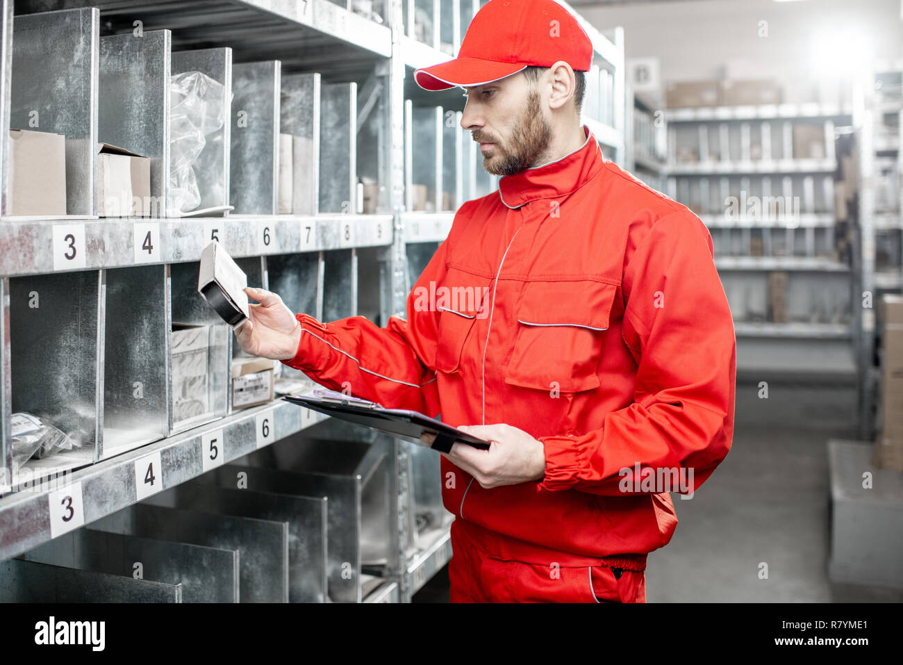 Warehouse worker in red uniform filling some documents checking goods ...