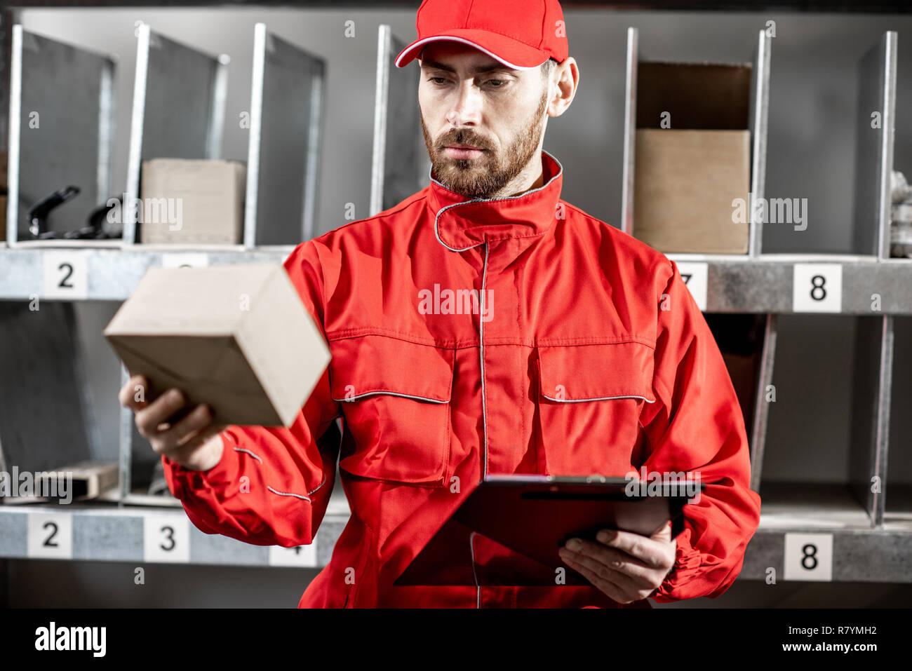 Warehouse worker in red uniform filling some documents checking goods ...