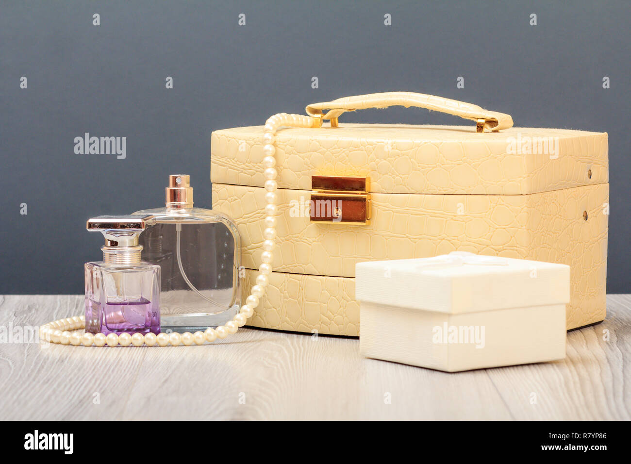 Cosmetic bag, bottles of perfume and gift box on wooden boards and gray ...