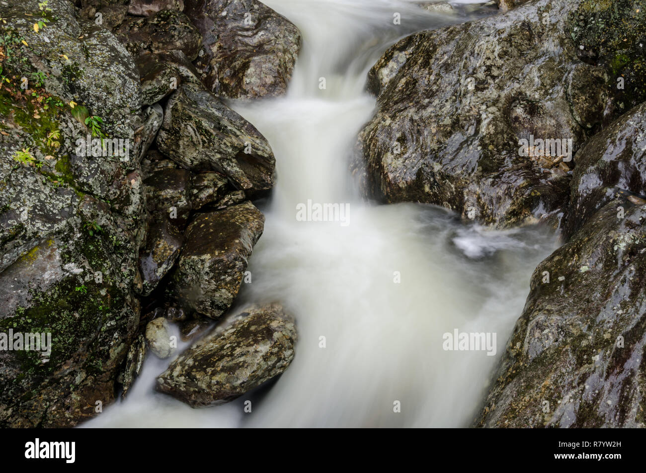 A long exposure shot of a rural stream pouring over granite rocks Stock ...