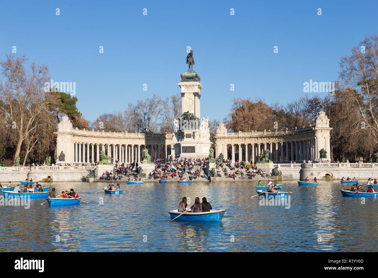 Tourists rowing traditional blue boats on lake in Retiro city park on a ...