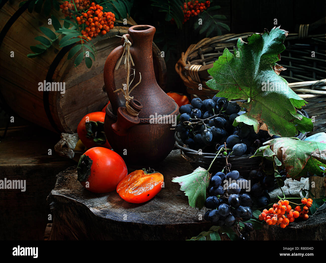 Still life with a jug, persimmon, rowan and grapes Stock Photo - Alamy